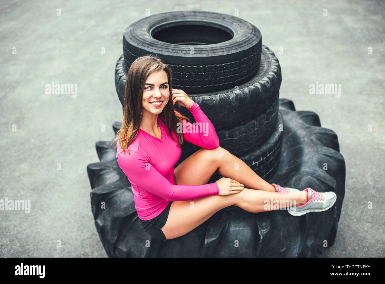 Sporty girl near huge old tires outdoor Stock Photo - Alamy