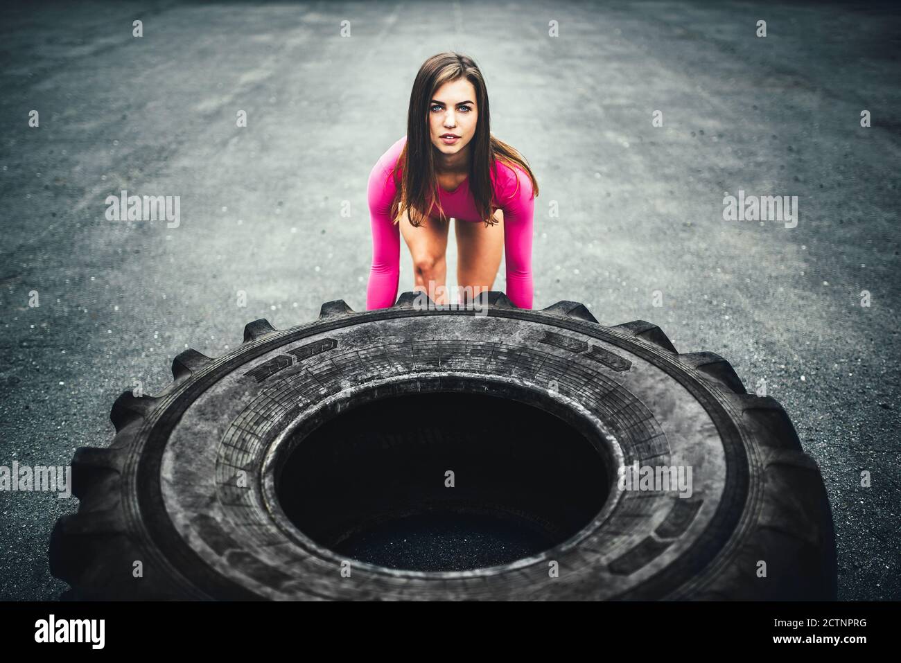 Pretty sporty girl lifting huge tire outdoor Stock Photo - Alamy