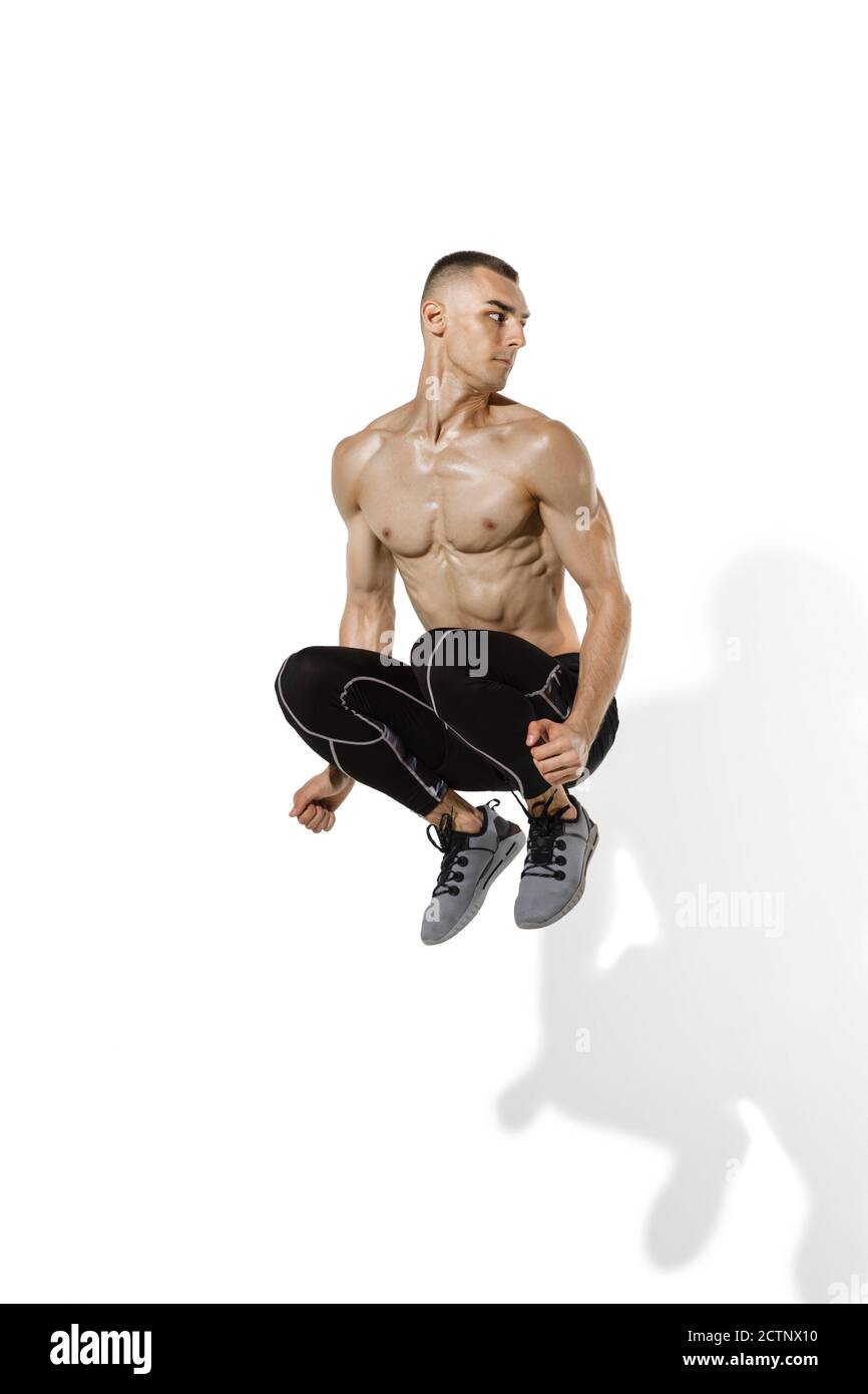 Jumping high. Stylish young male athlete practicing on white studio ...