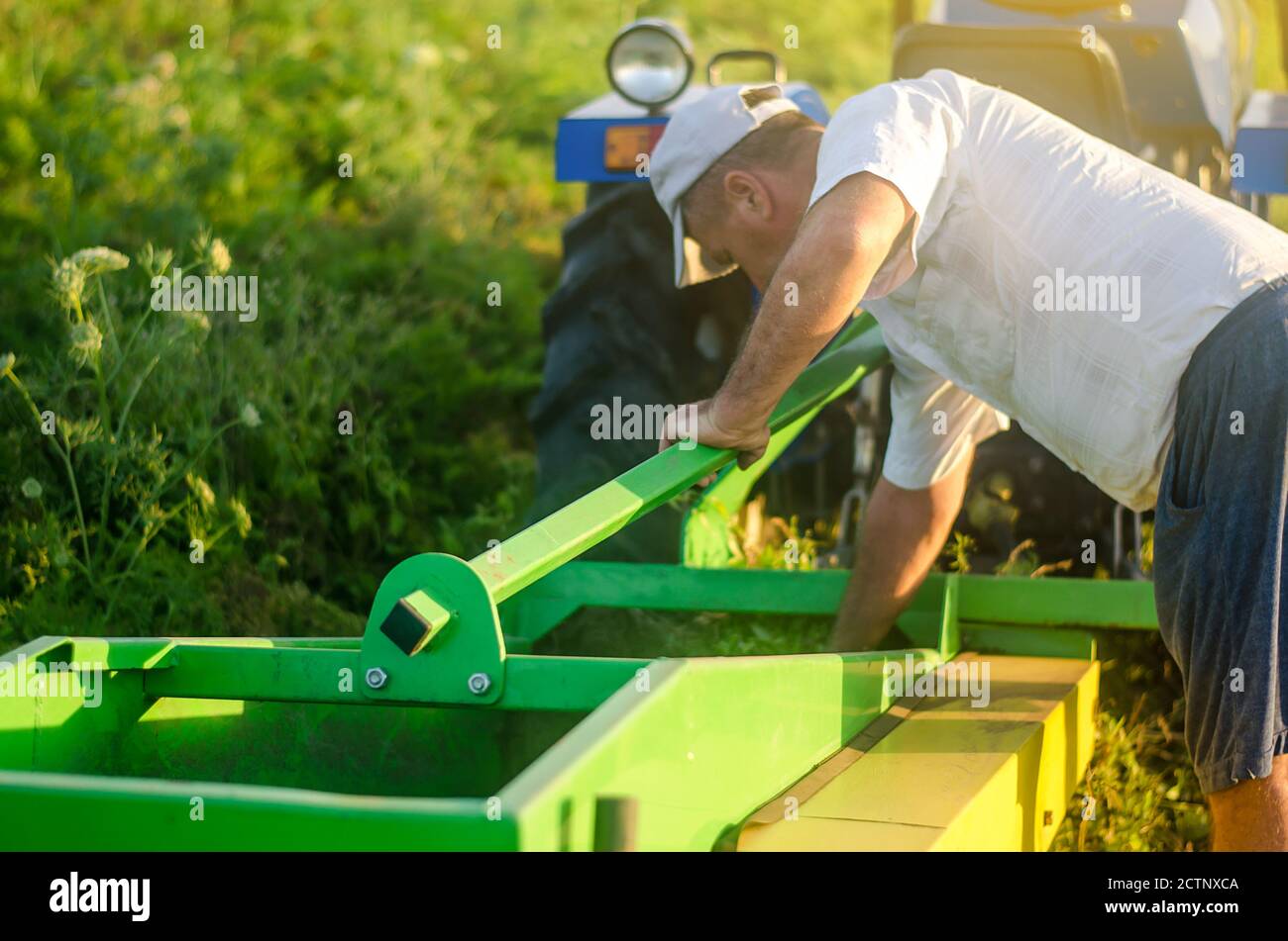 A farmer examines the process of digging up potato tubers with a digger ...