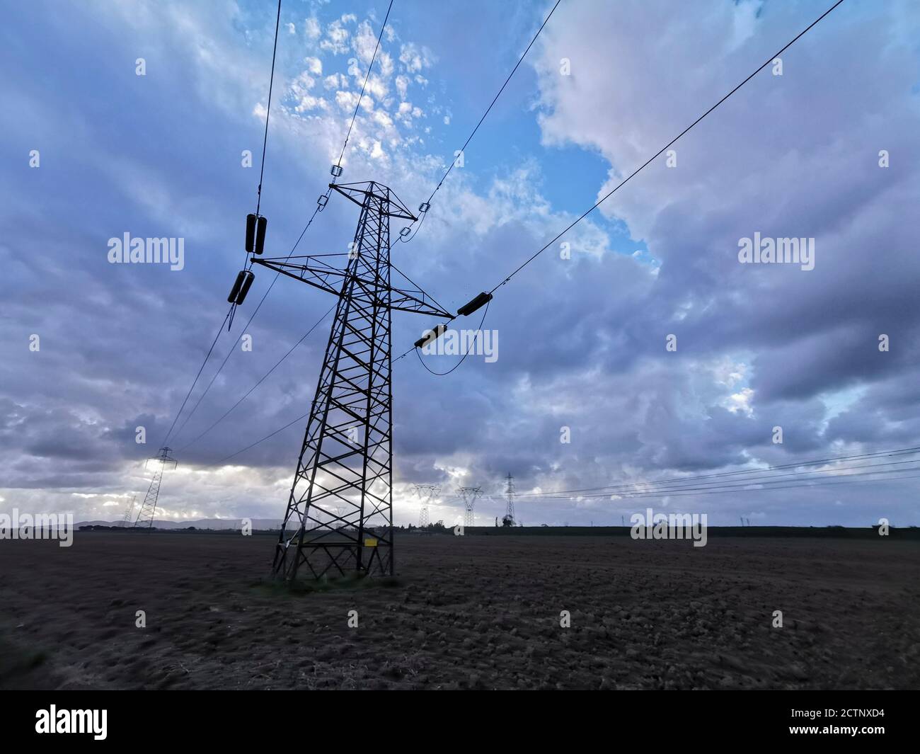 high voltage pylon on cloud background in hills of tuscany livorno ...