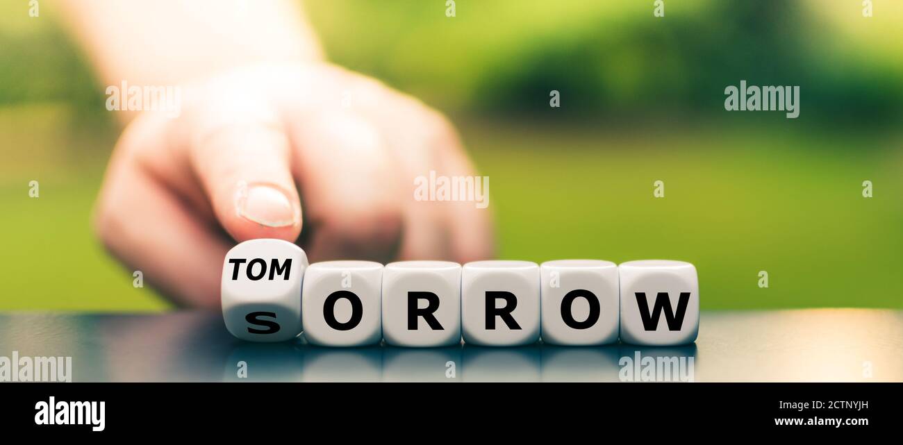 Hand turns dice and changes the word "sorrow" to "tomorrow". Symbol for ...