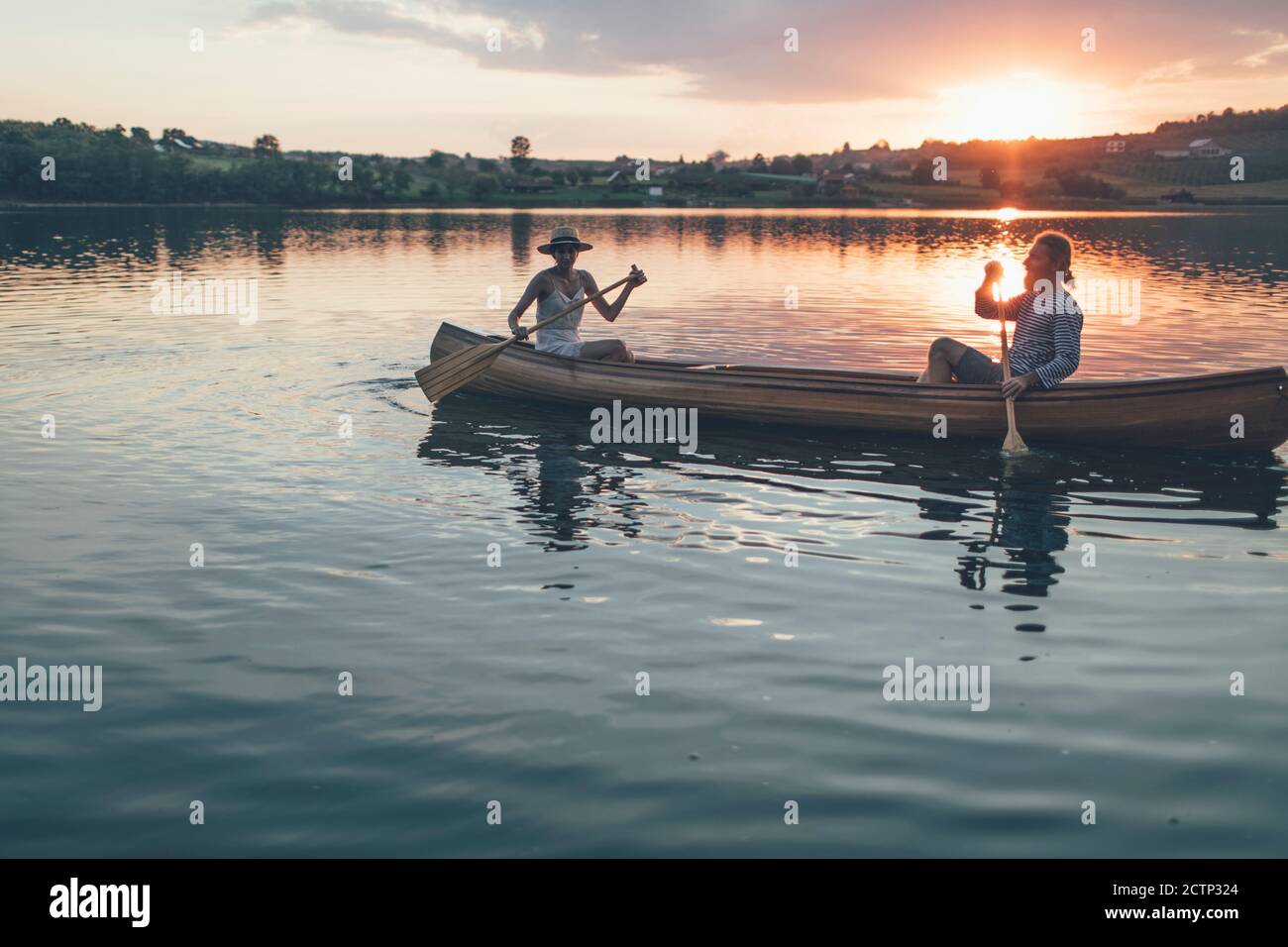 Romantic couple paddling canoe on the sunset lake Stock Photo - Alamy