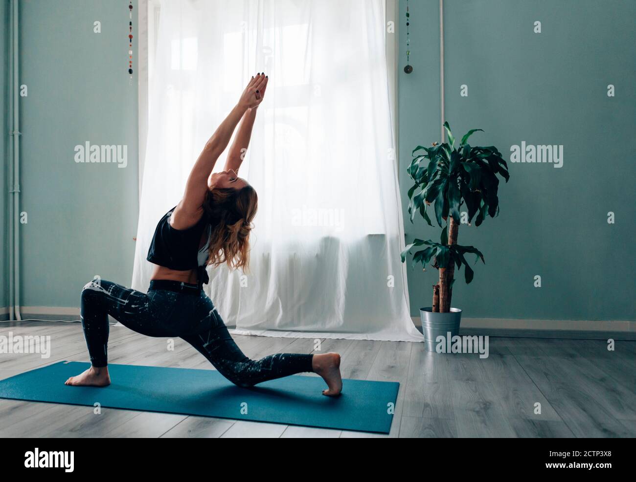 woman in sportswear doing yoga exercise with her arms raised and hands ...