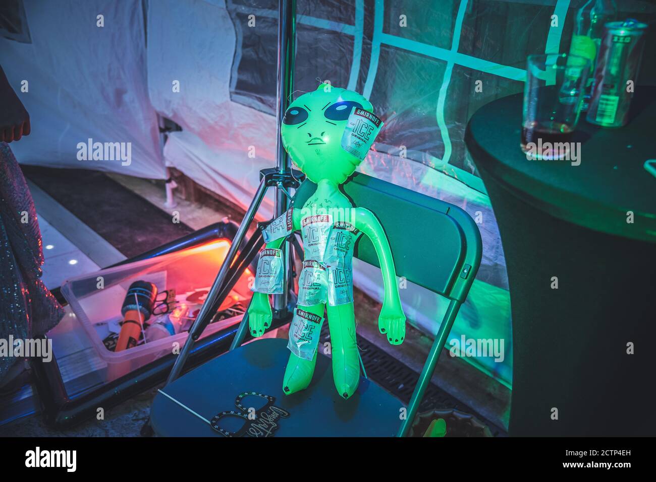 A green inflatable alien covered in vodka stickers from a drinking game ...