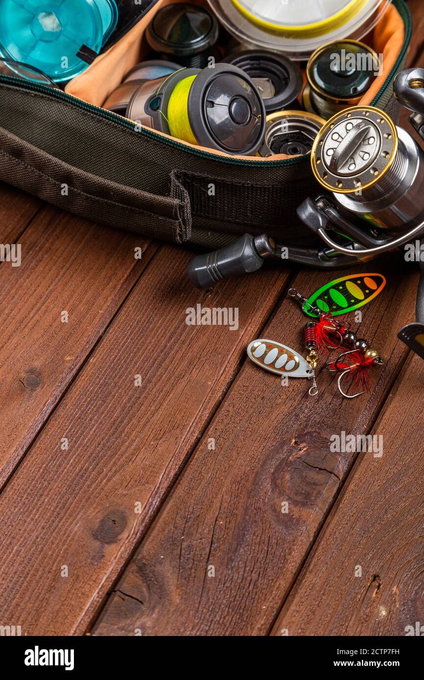 Different fishing tacles with lures and reels on wooden brown ...