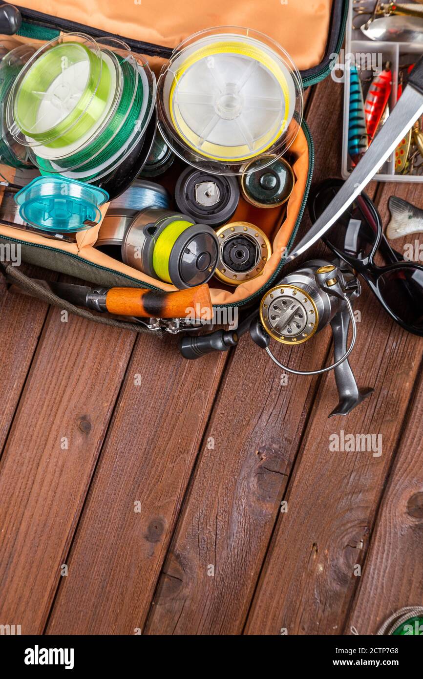 Different fishing tacles with lures and reels on wooden brown ...