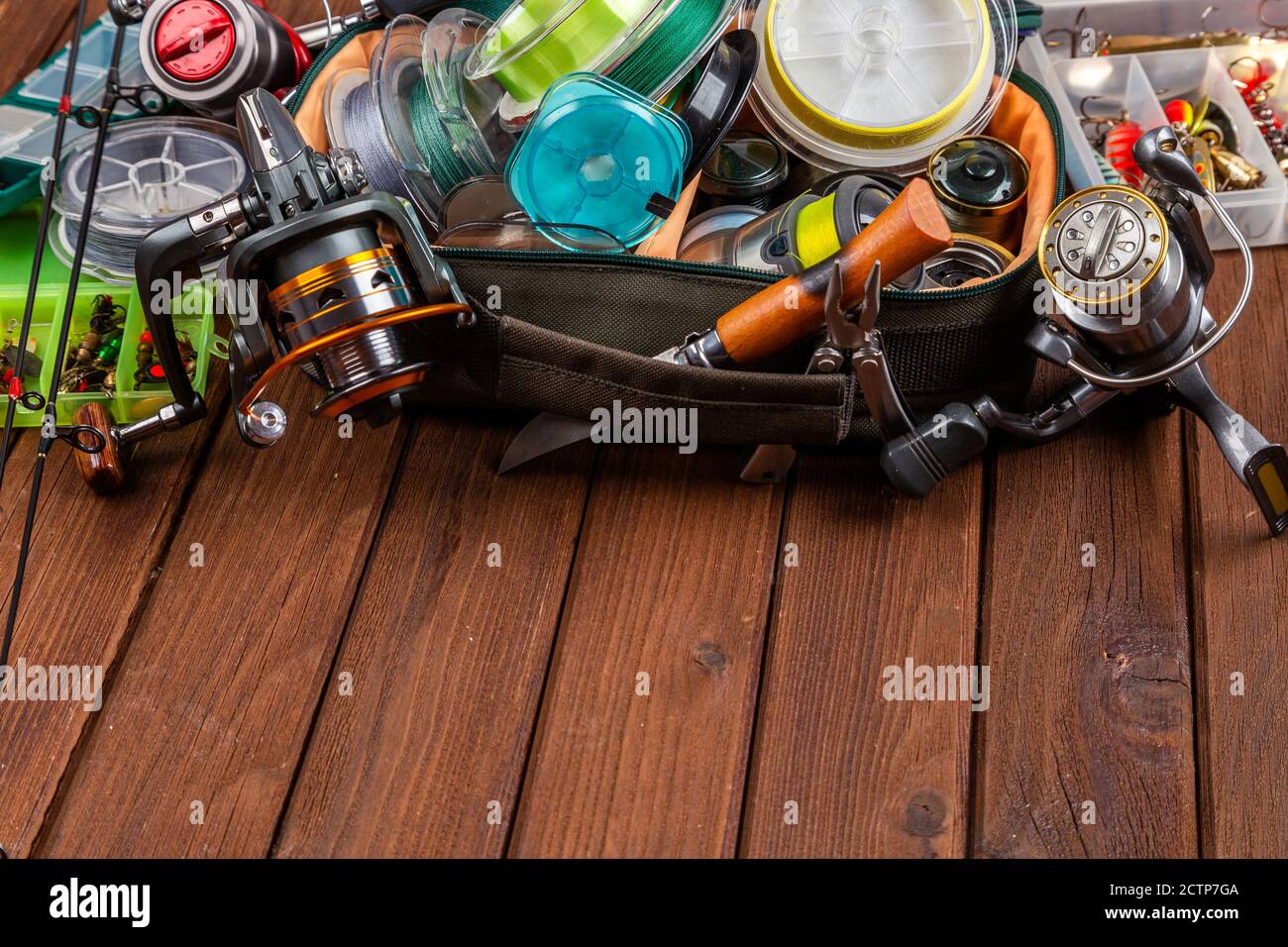 Different fishing tacles with lures and reels on wooden brown ...