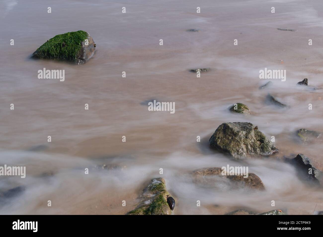 Stones at the beach surrounded by smooth water Stock Photo - Alamy