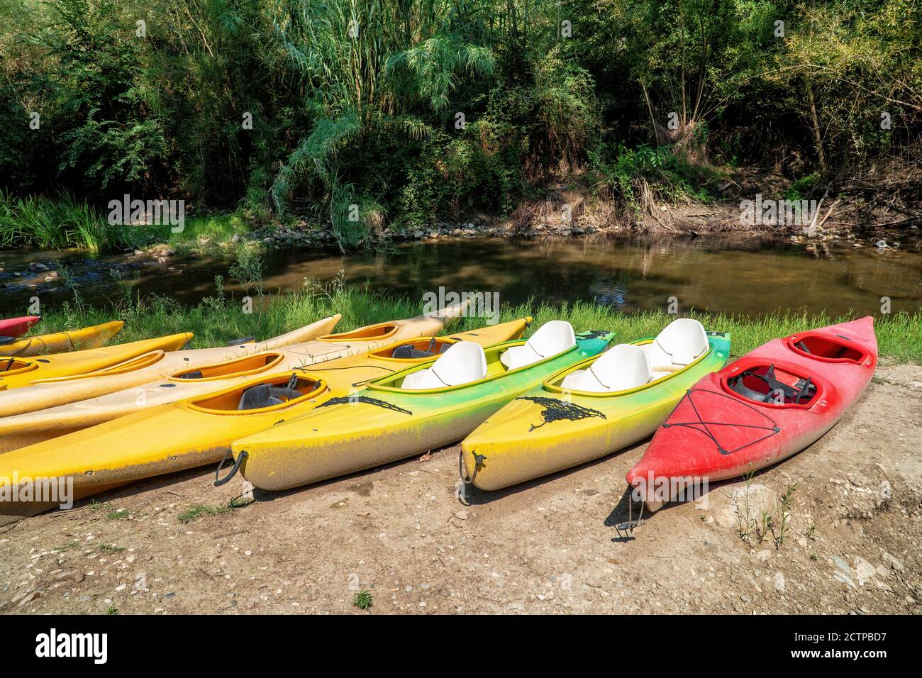 A set of ten old and worn kayak of various color on the riverside Stock ...