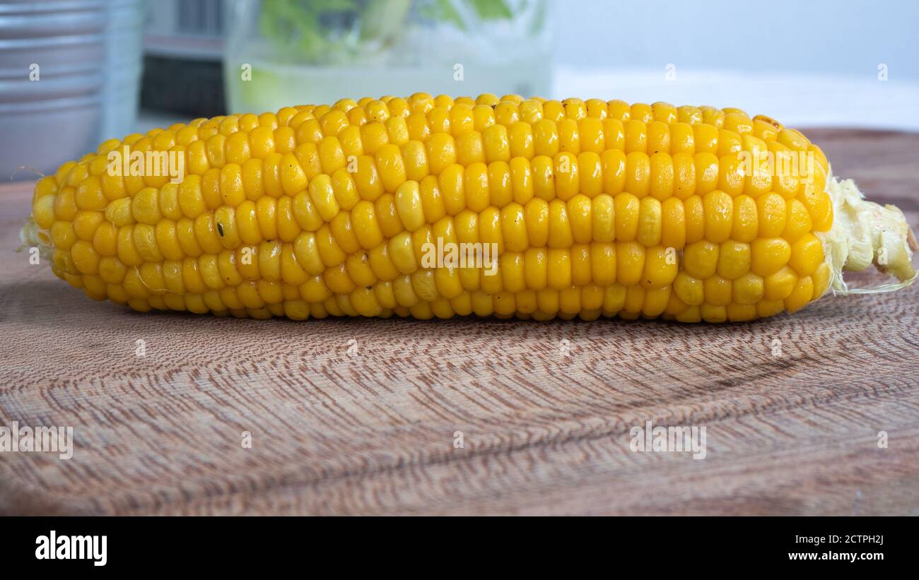 A delicious corn on the cob captured laying on a wooden board. The ...