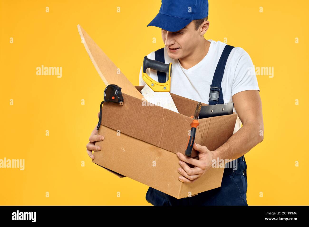 worker with box in hand tools loader yellow background Stock Photo - Alamy