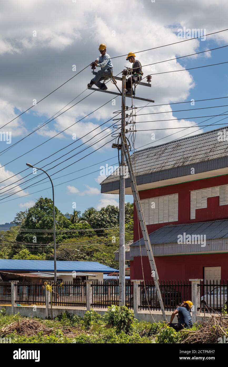 Tenhilan, Sabah, Malaysia: Two linemen doing repair work on top of a ...