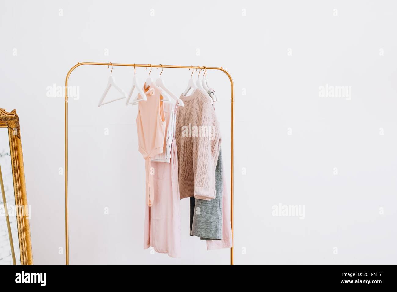 Gold floor wardrobe rack with pastel color fashion clothes near white ...