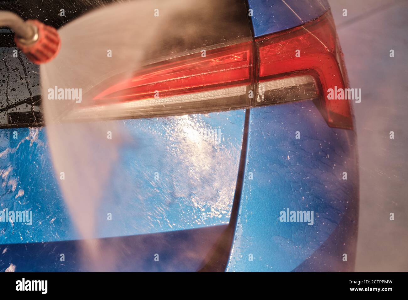 Back view of a blue car washing under high pressure water. Self service ...