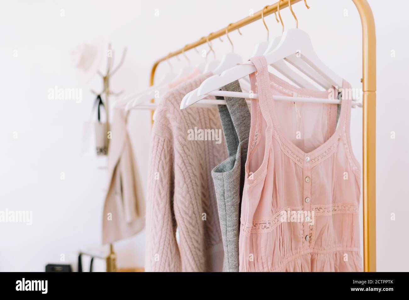 Gold floor wardrobe rack with pastel color fashion clothes near white ...