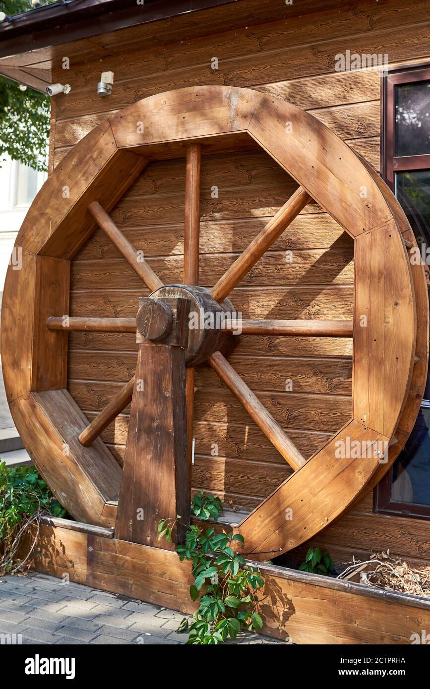 Decorative sunlit wooden mill wheel in a city street Stock Photo - Alamy