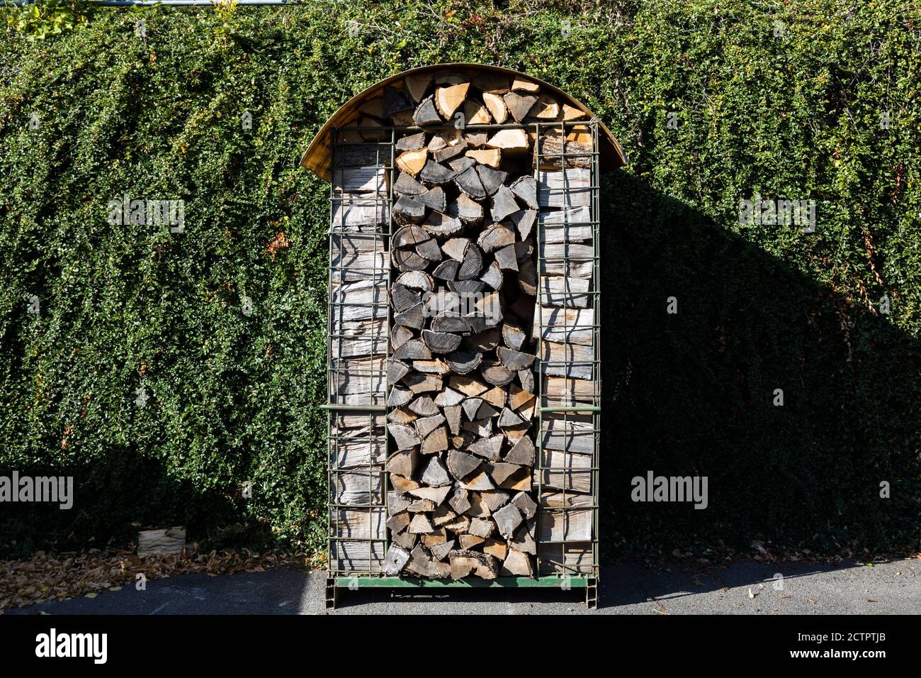 Fun metal wire log store with curved roof and packed with cut logs ...