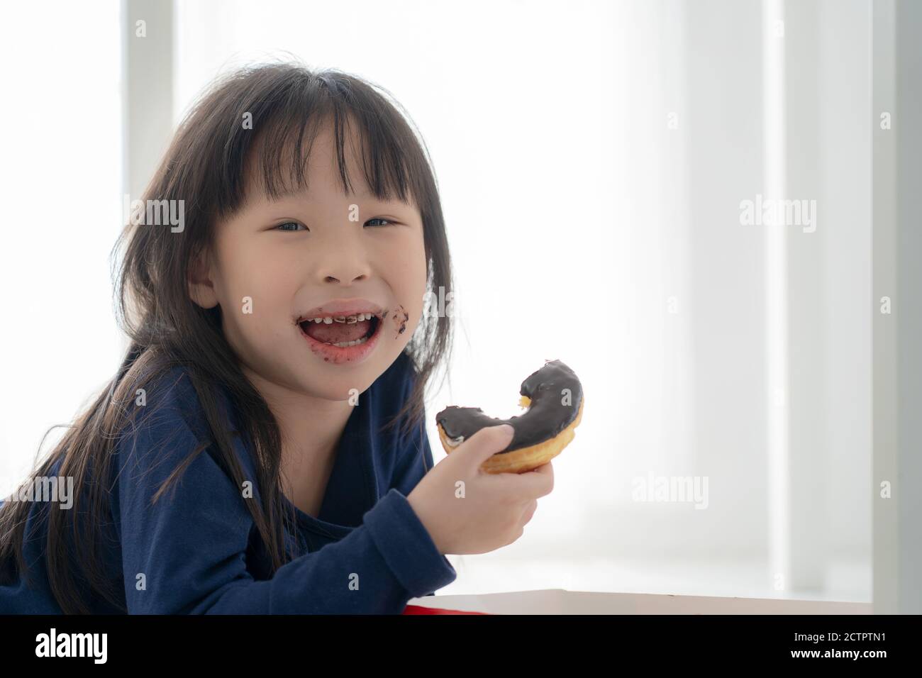 Close up face of hungry little Beautiful Asian girl eating chocolate ...