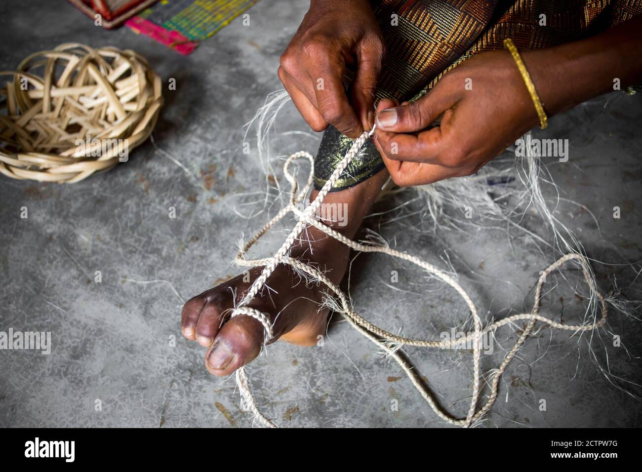 An woman is making a rope from the fibers of a banana tree with the ...