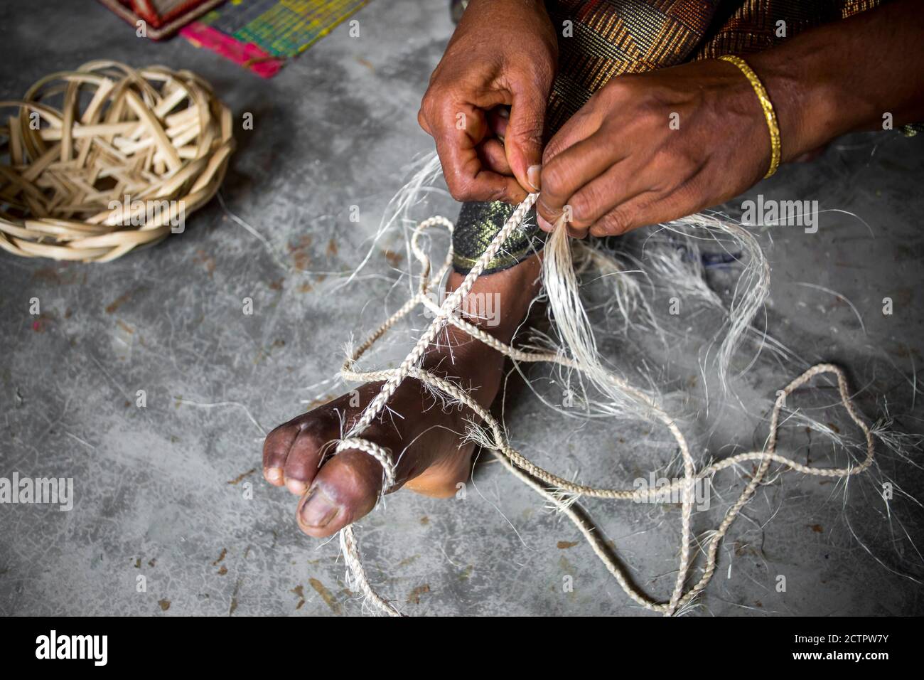 An woman is making a rope from the fibers of a banana tree with the ...