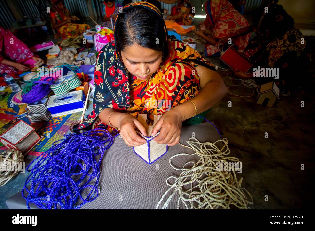 Bangladesh – May 13, 2018: A woman crafts maker is making a showpiece home from the fibers of a ...