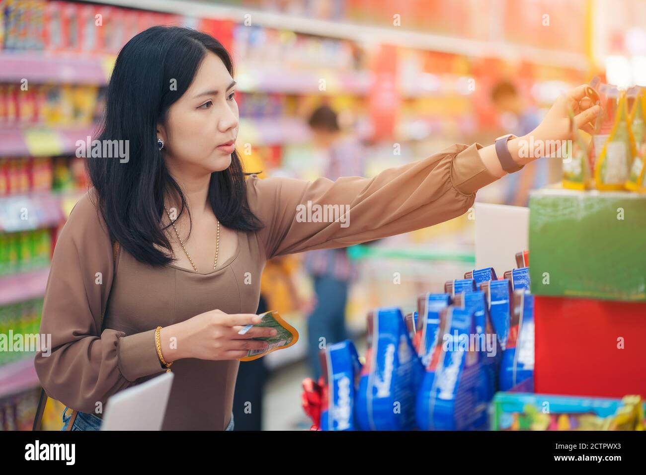 woman making shopping decision for sweet in supermarket, stands in ...