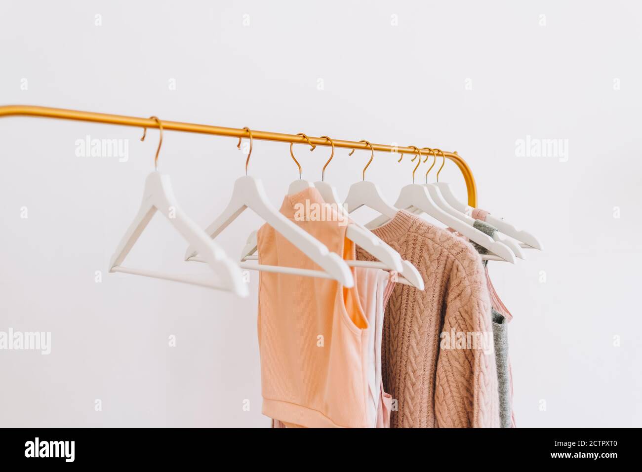 Gold floor wardrobe rack with pastel color fashion clothes near white ...