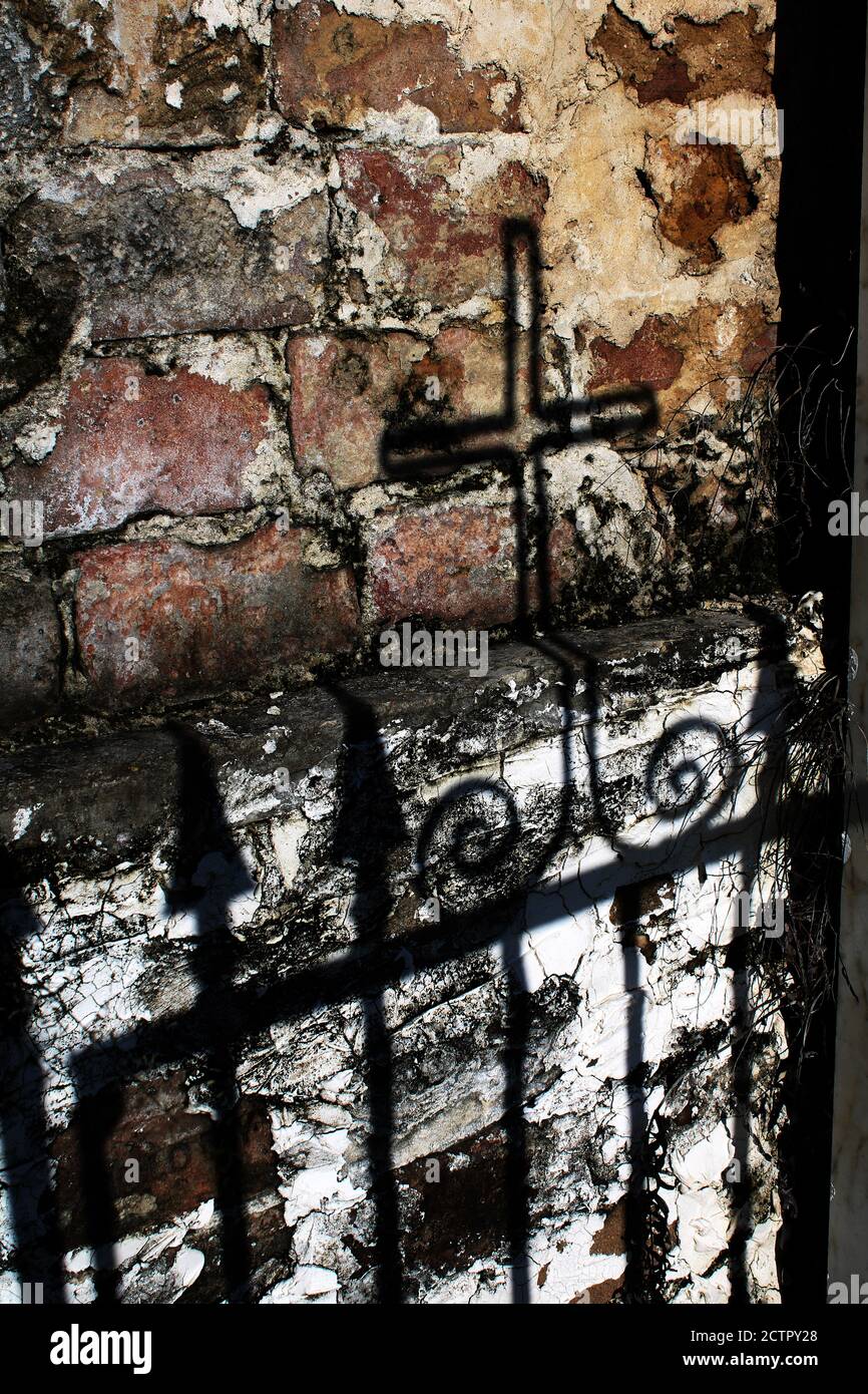 this shadow of a cross is cast upon exposed brick out from behind old ...