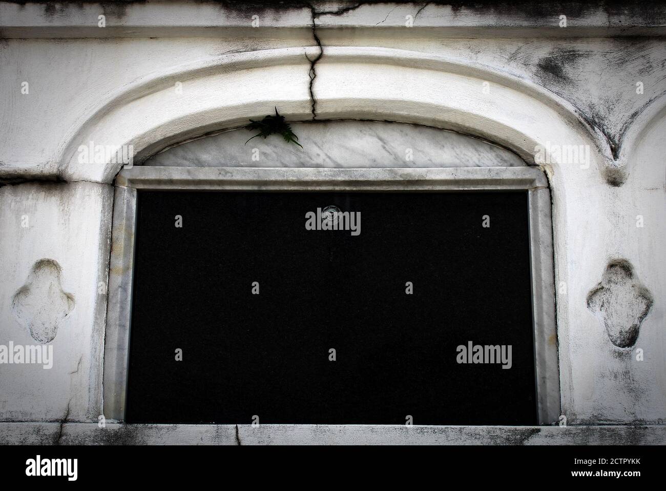 a dark spooky mysterious unmarked black tombstone within an old cracked ...