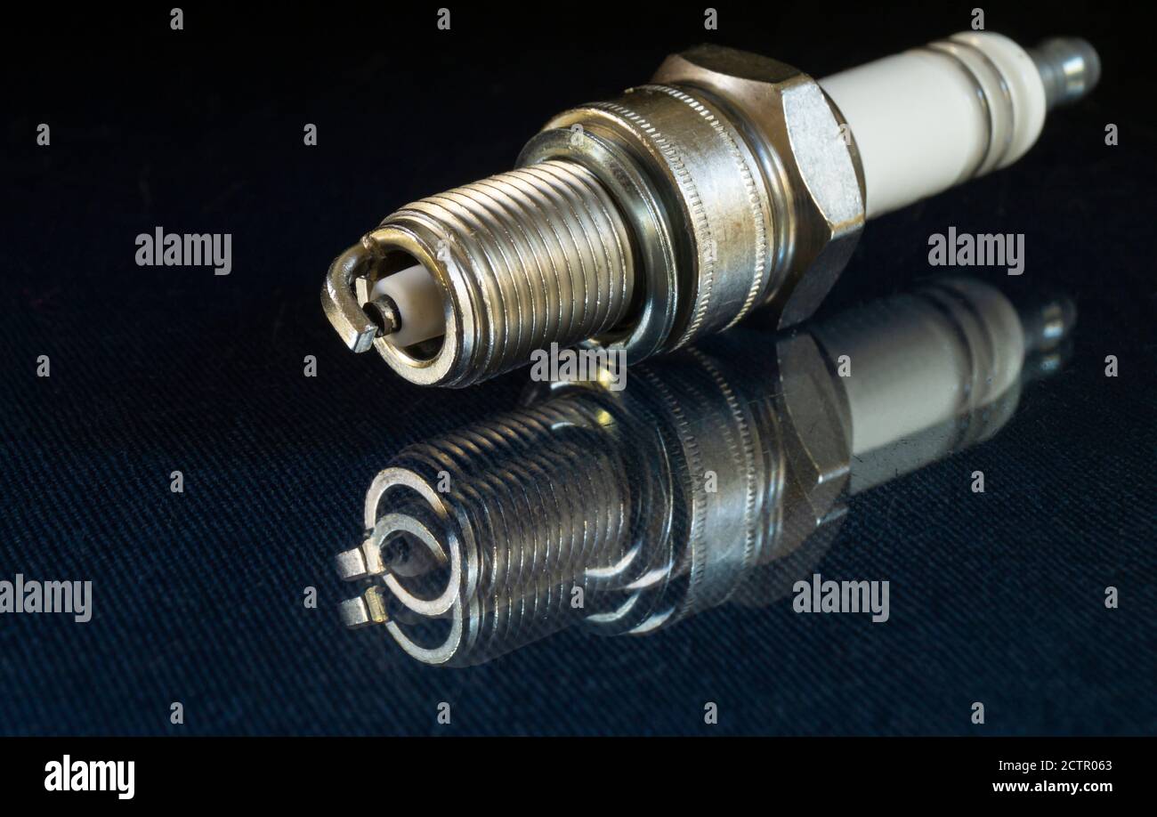 The Spark plug for car on black background. Detail rests upon glass ...
