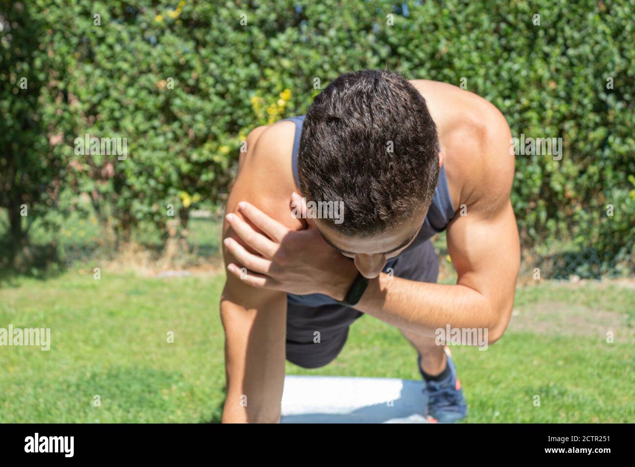 detail of a young muscular man doing a flexion on one arm in the garden ...