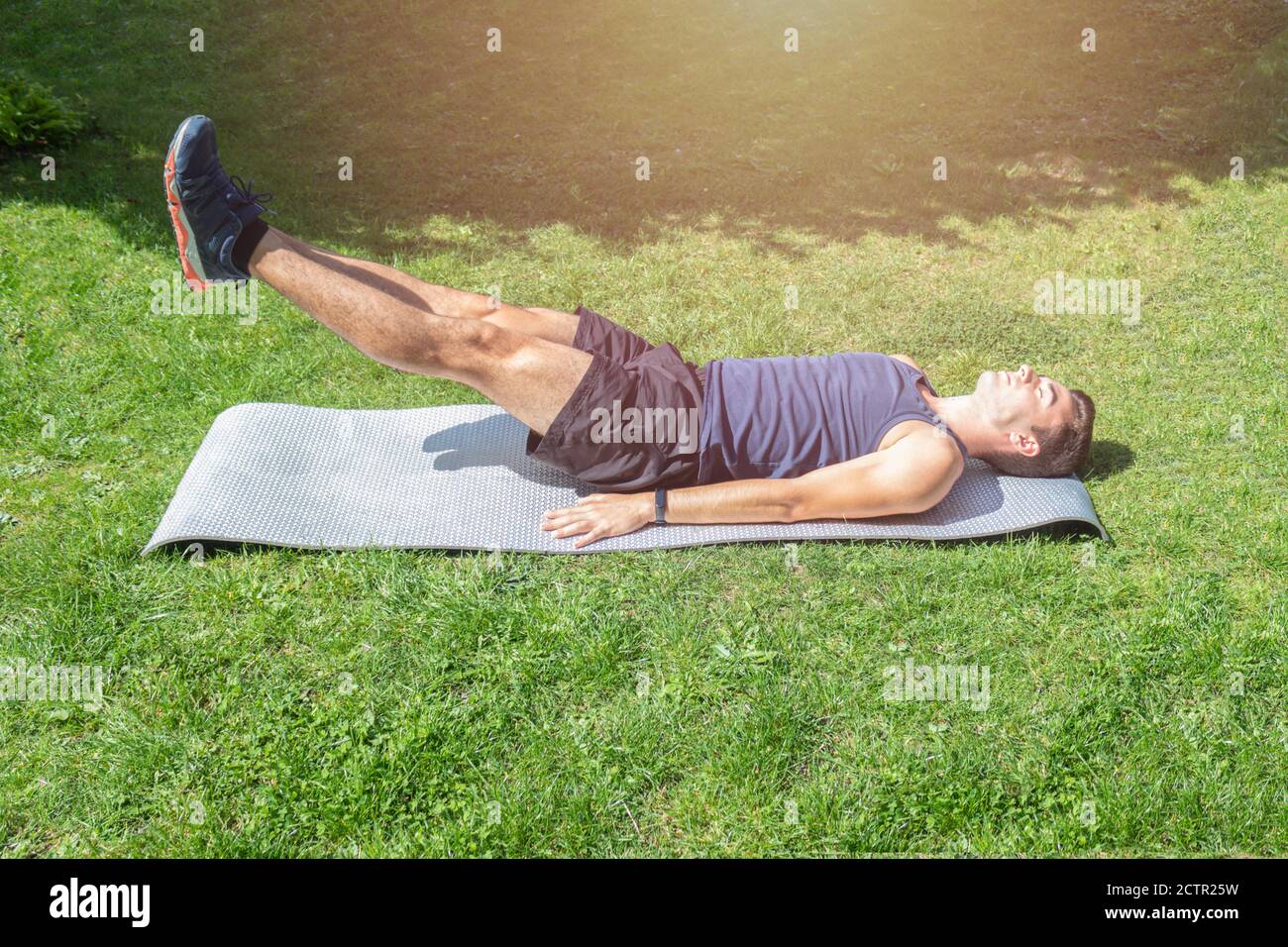 young man lying on a mat doing bodybuilding exercises and abdominal ...