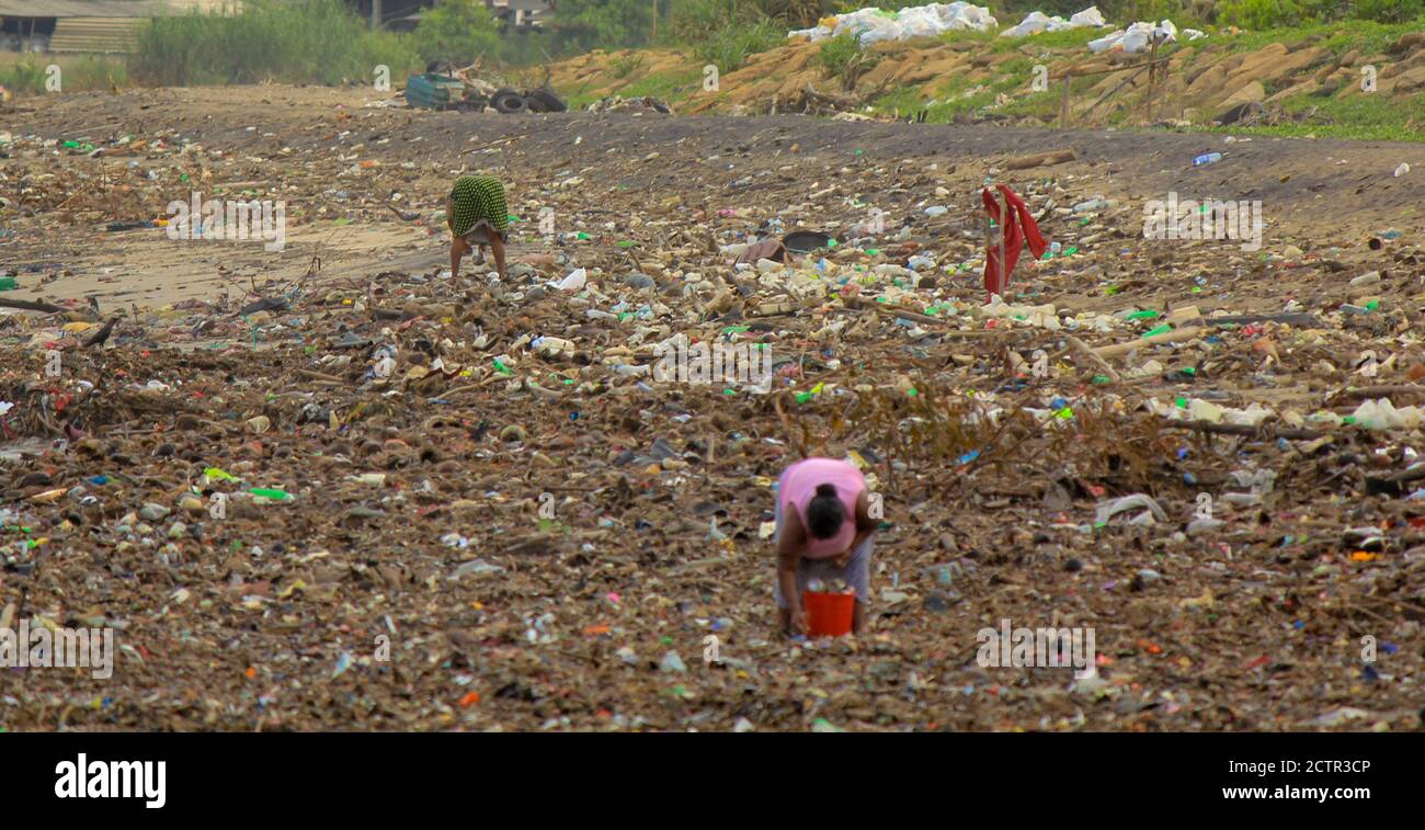 Sea Pollution: women collects plastic things in a pile of garbage ...