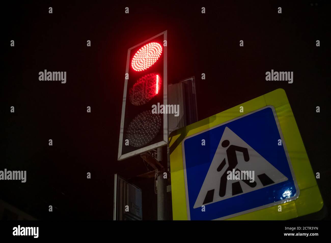 Red traffic light, near pedestrian crossing sign at night close-up ...