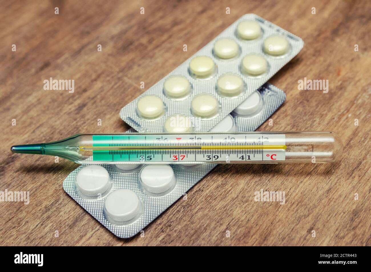 Tablets lie next to a thermometer to measure the temperature of a human ...