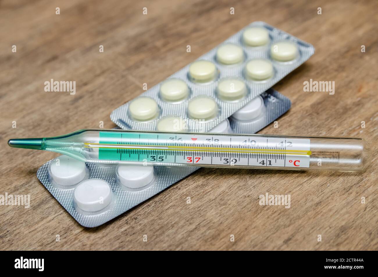 Tablets lie next to a thermometer to measure the temperature of a human ...