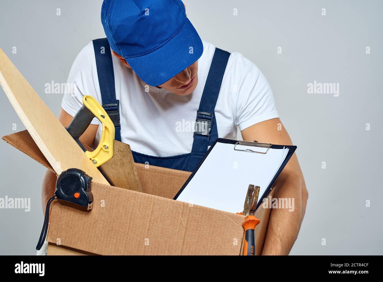 man in working uniform with a box in his hands tools loader delivery ...