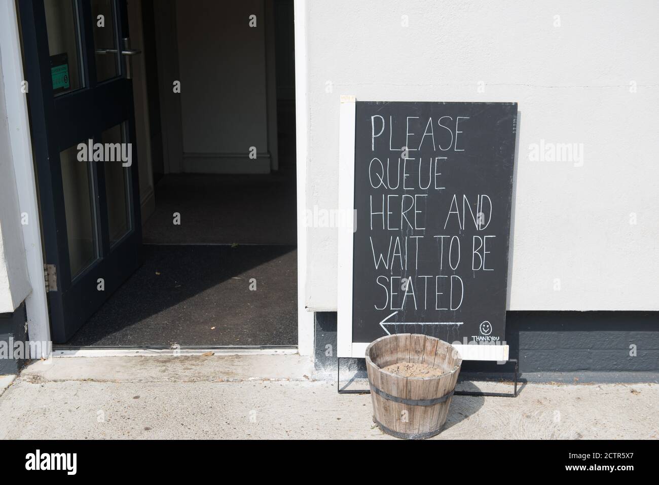 Please Queue Here sign at restaurant requesting that customers wait to ...
