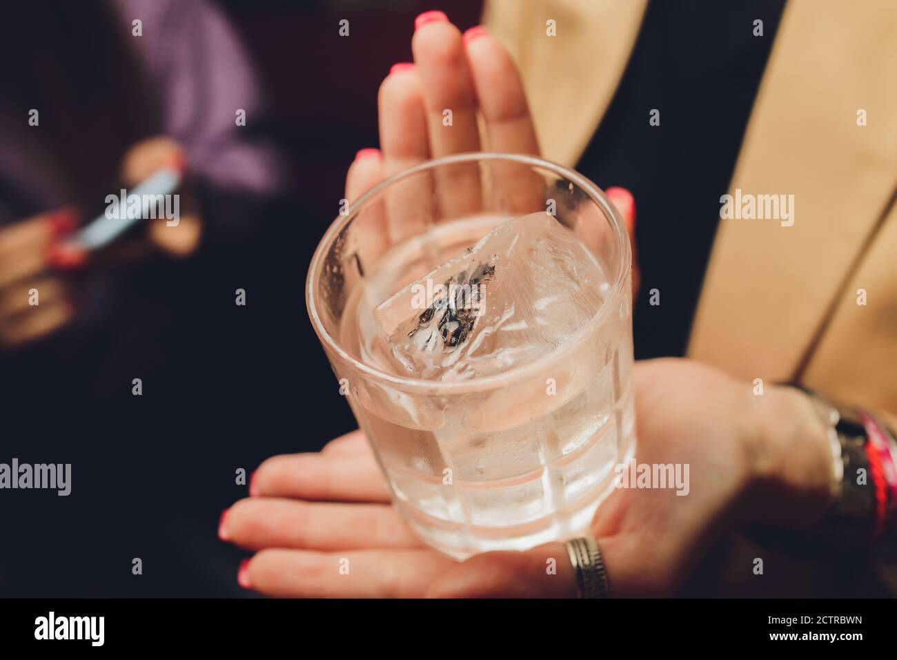 Female hands holding a clear glass of water. Slime body on background ...