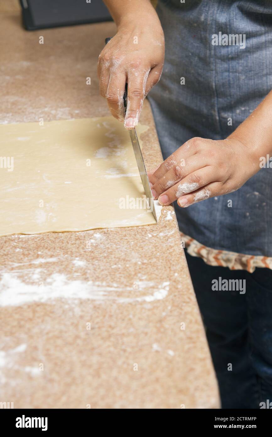 unrecognizable person cutting flour dough on granite plateau or table ...