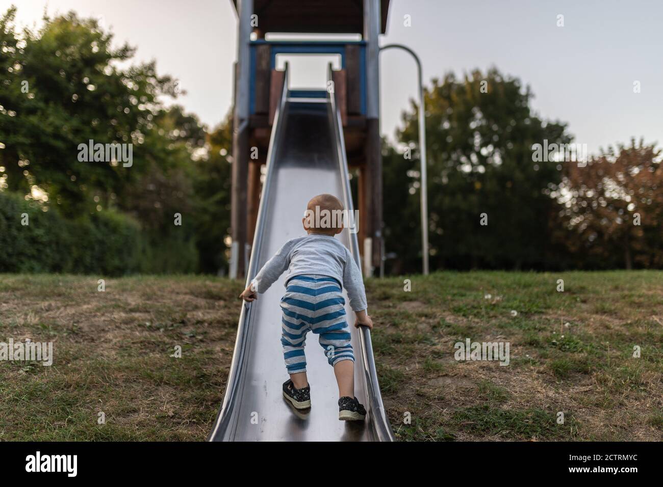 Young boy climbing up on a slide Stock Photo - Alamy