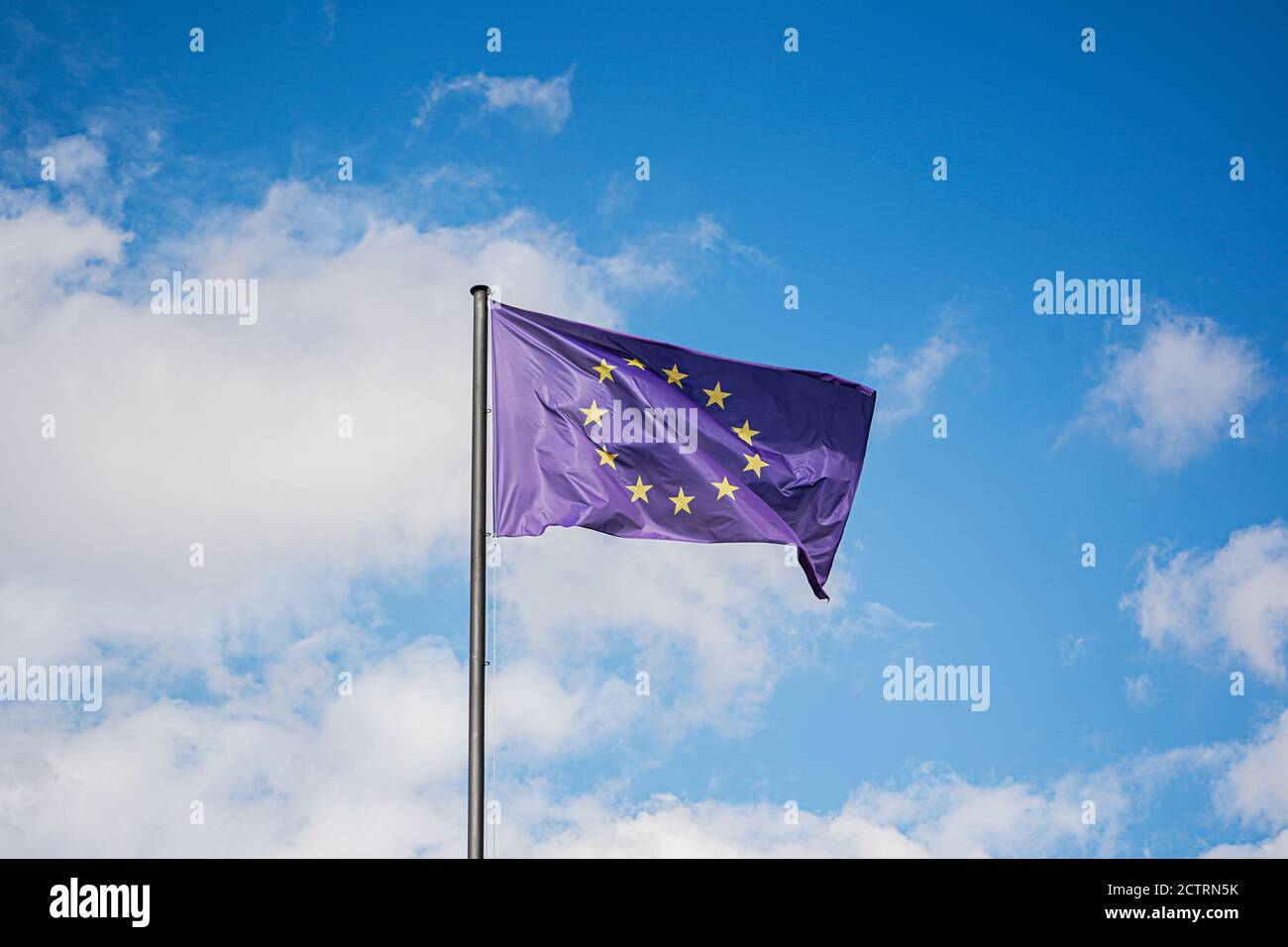 Low angle shot of the wavy Flag of Europe on a pipe under a blue cloudy ...