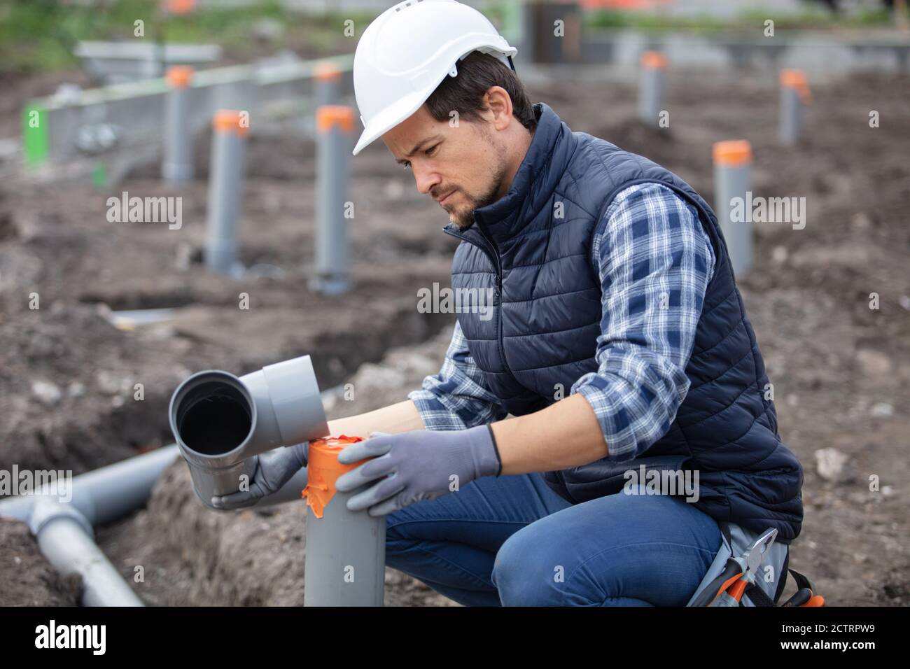 young construction worker installing pipes at site Stock Photo - Alamy