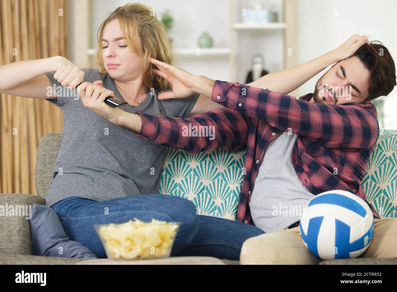 angry couple fighting over tv control remote Stock Photo - Alamy