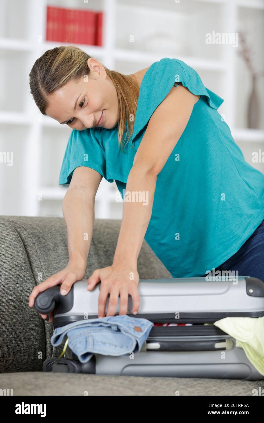 woman trying to compress things in the suitcase Stock Photo - Alamy