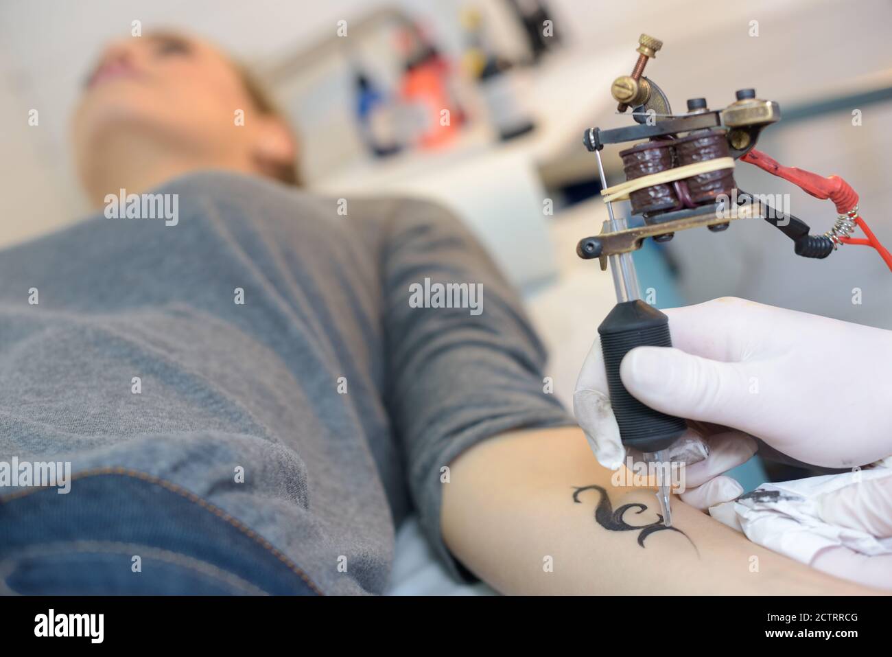 Woman having tattoo on arm Stock Photo - Alamy