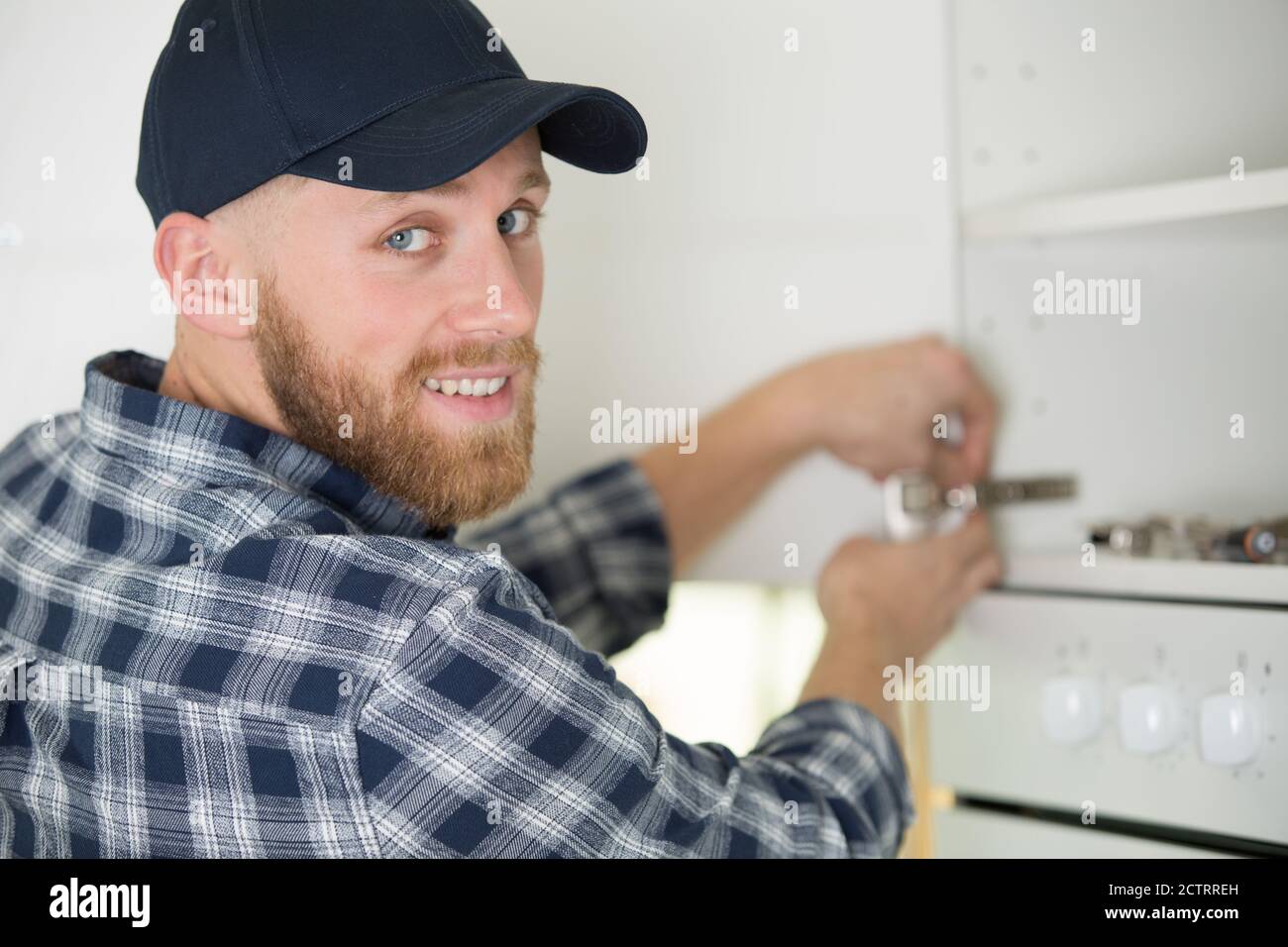 man fitting hinge to kitchen corner cupboard base unit Stock Photo - Alamy