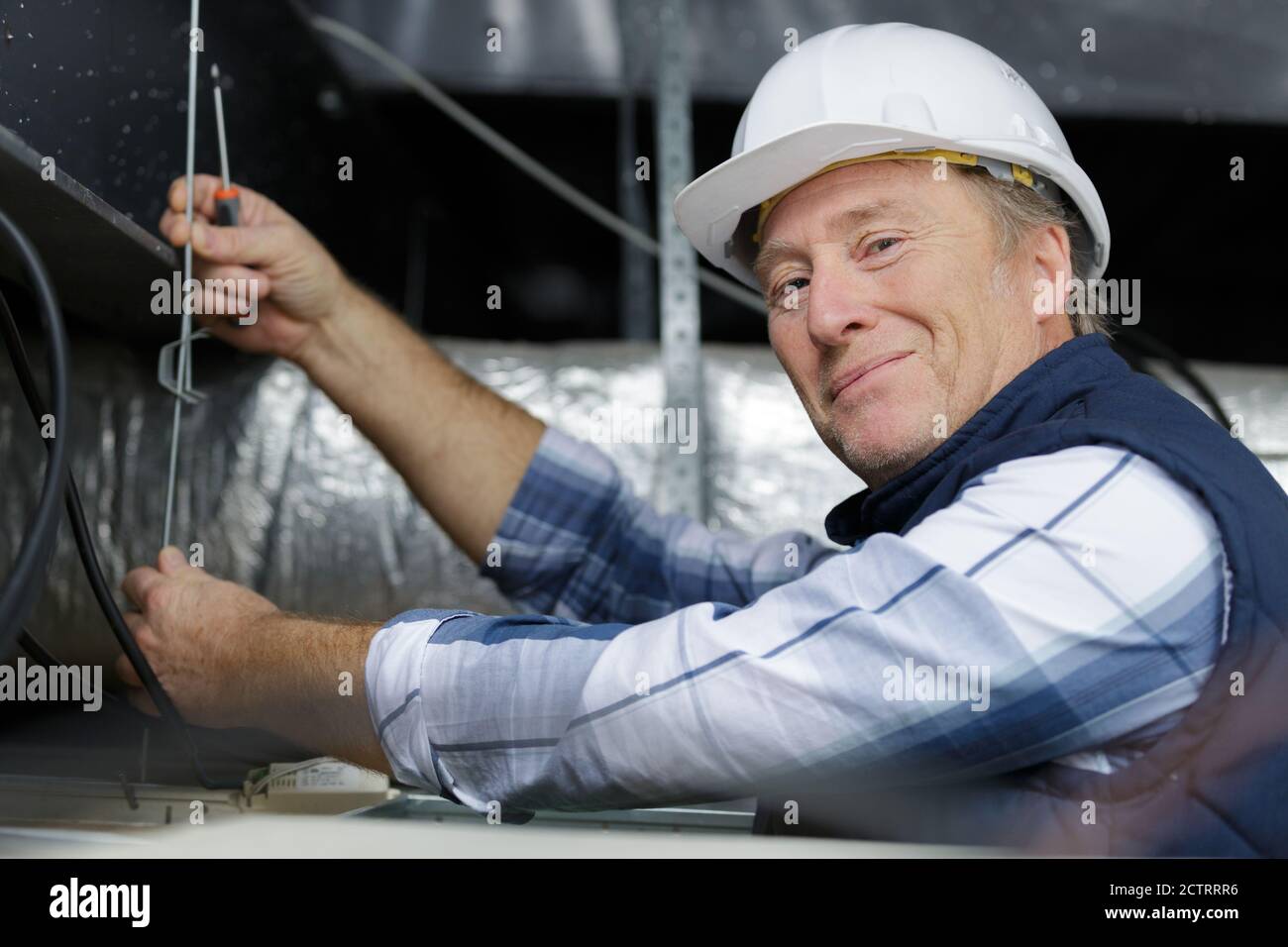 happy builder fixing a wire issue Stock Photo - Alamy