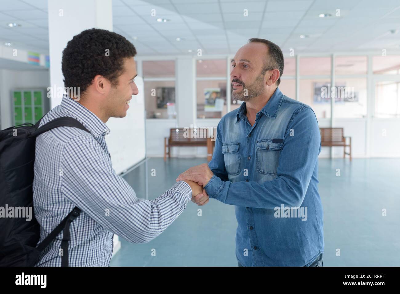 man welcoming young visitor with a warm handshake Stock Photo - Alamy